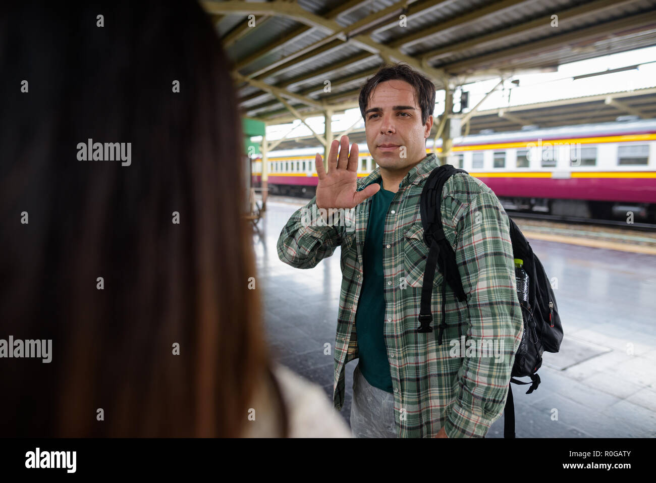 Man waving to young Asian tourist woman in train station Stock Photo ...