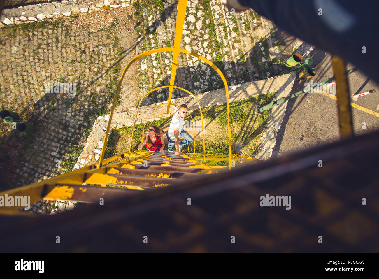 Young friends are having fun while climbing metal ladder looking up on ...