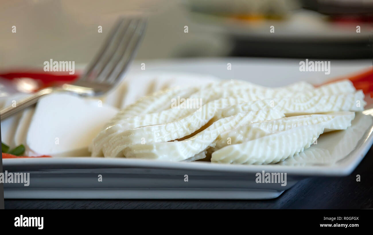 White sliced white cheese close-up on a blurred background. Side view ...