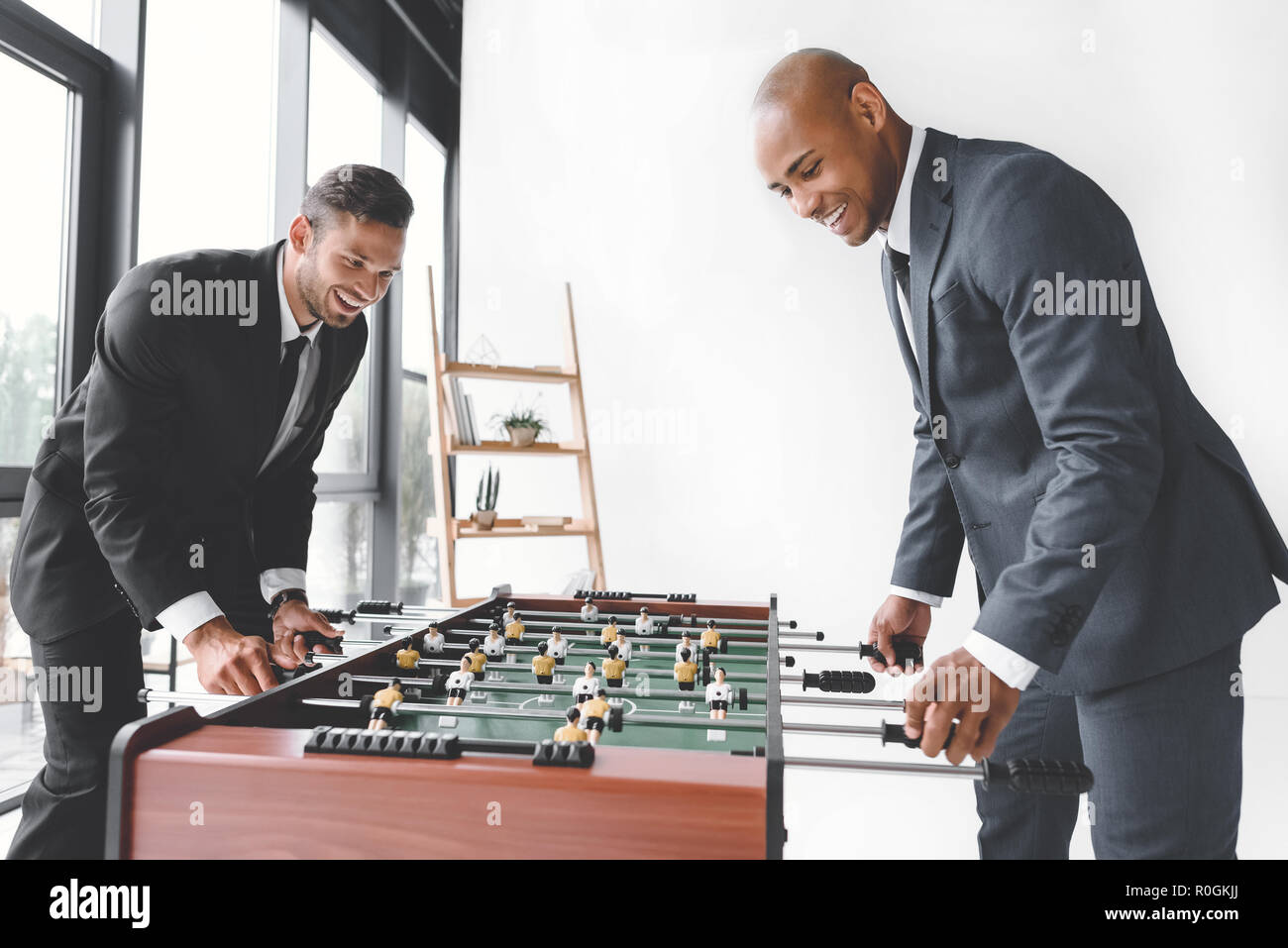 side view of happy businessmen playing table football together Stock ...