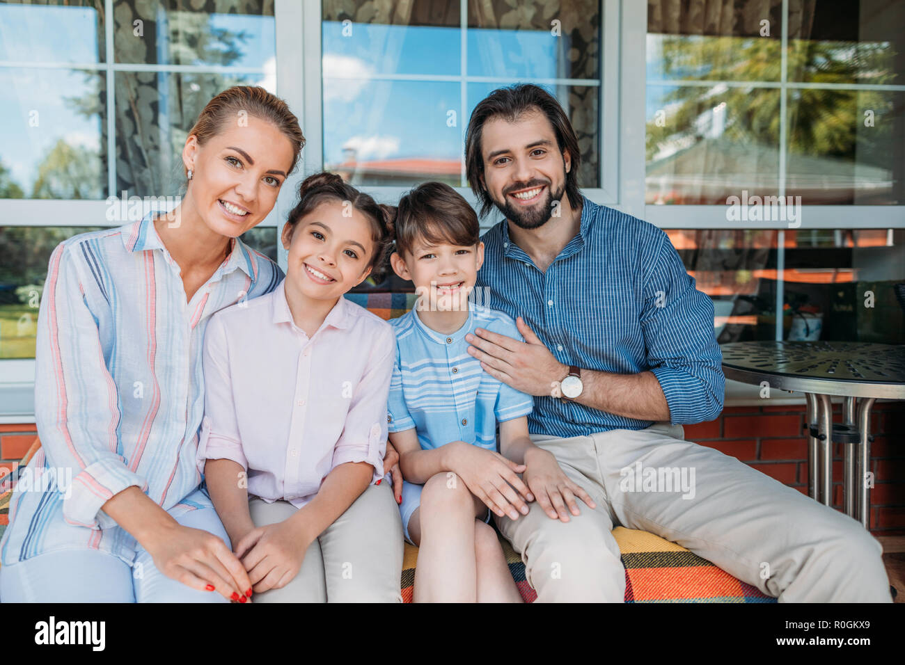 portrait of smiling family sitting on sofa together on country house ...