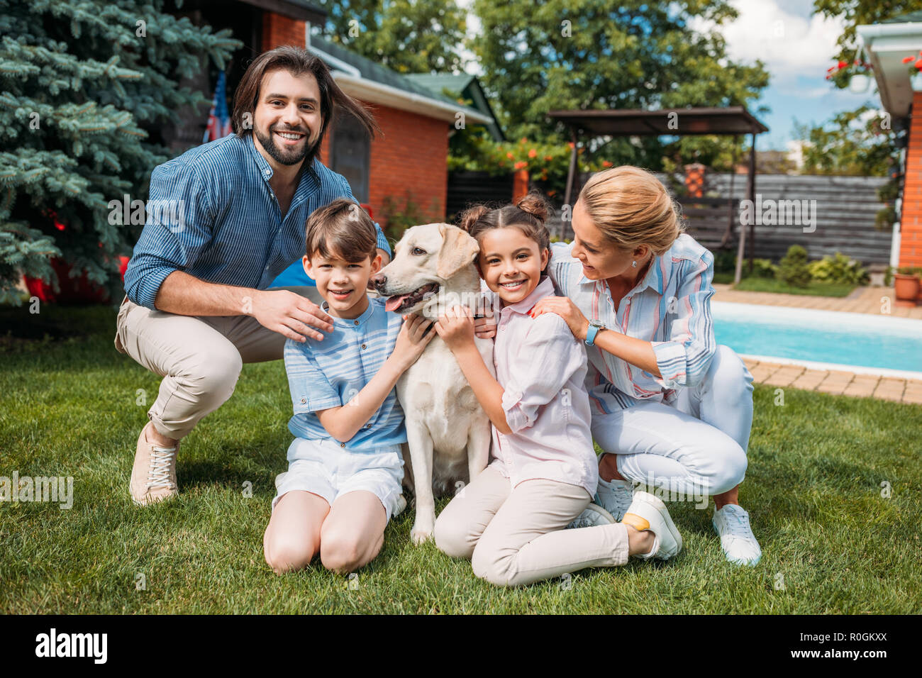 happy family with labrador dog looking at camera while spending time on ...