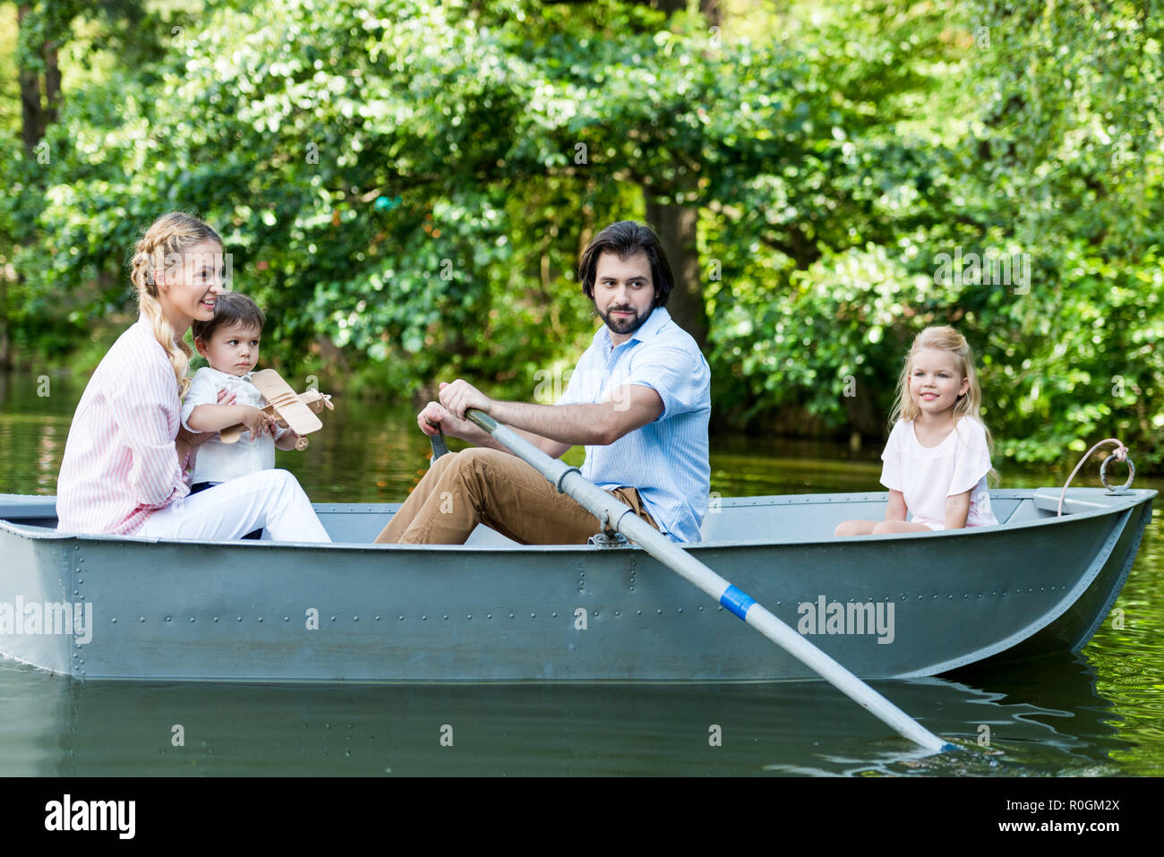 side view of young family riding boat on river at park Stock Photo - Alamy