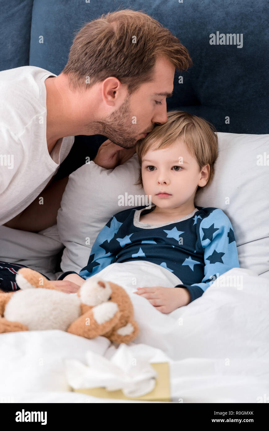 father checking sons temperature with lips while he lying in bed Stock ...