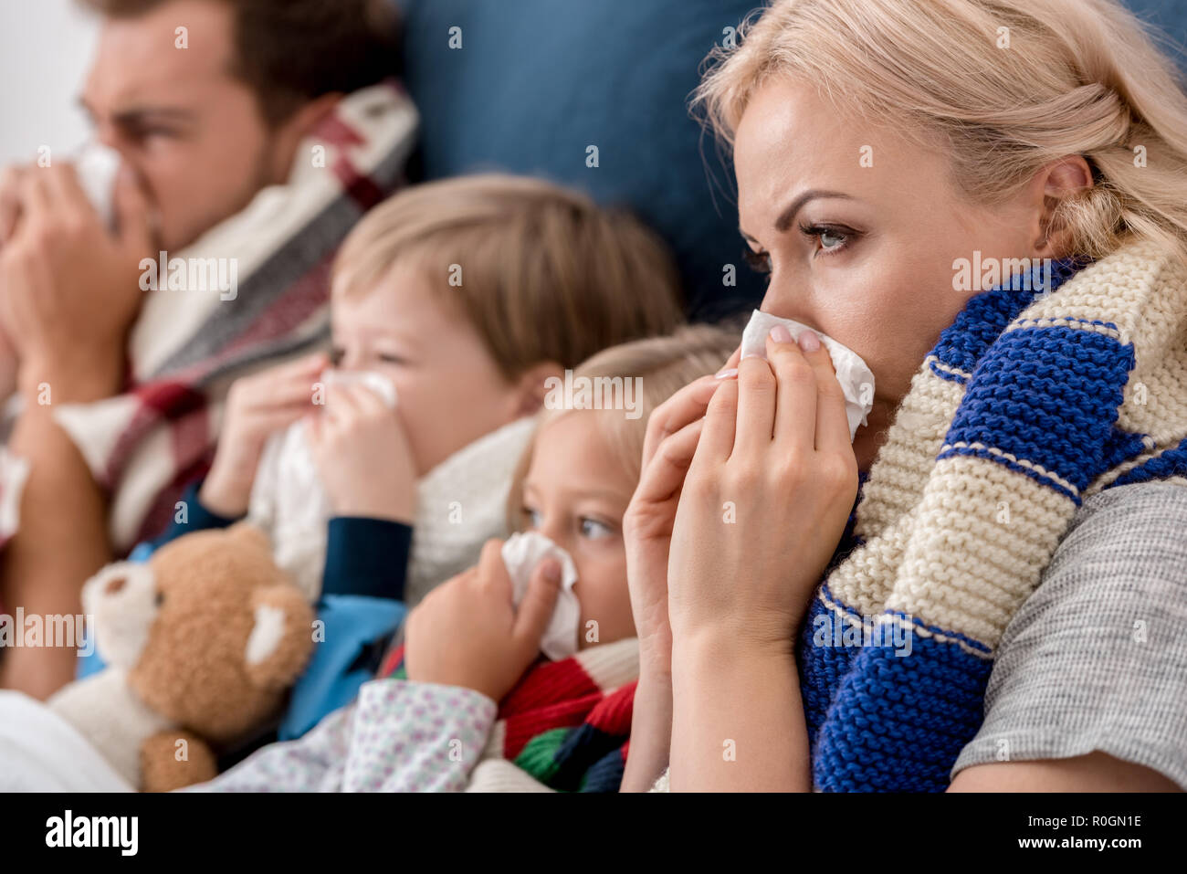 close-up shot of sick young family blowing noses with napkins together ...