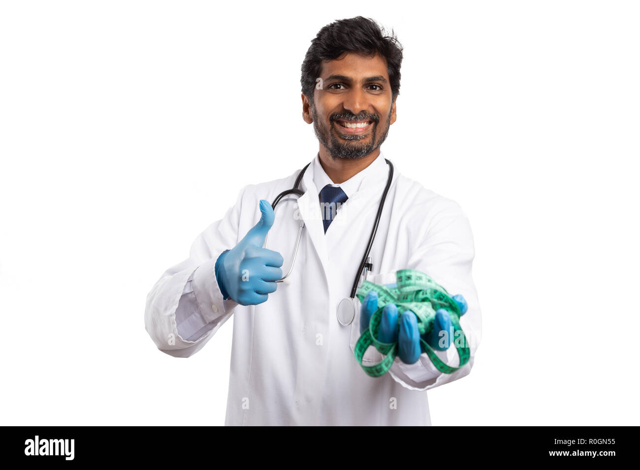 Smiling indian medic man holding measurement tape with thumb up as ...