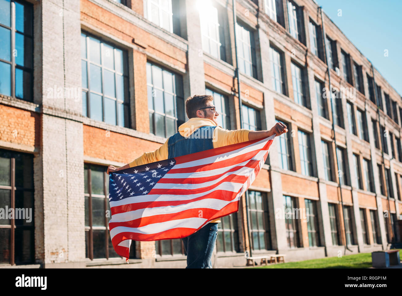 back view of young man with american flag in hands on street Stock ...