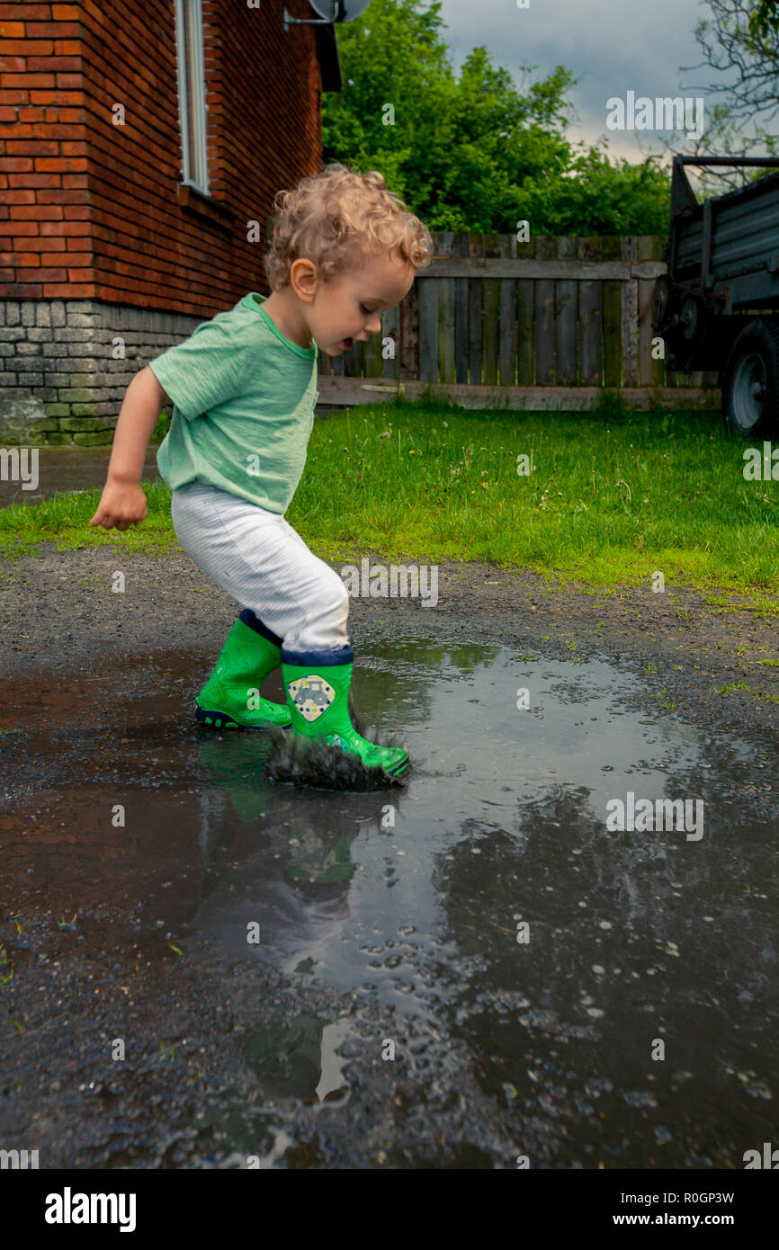 Boy playing in puddle Stock Photo - Alamy