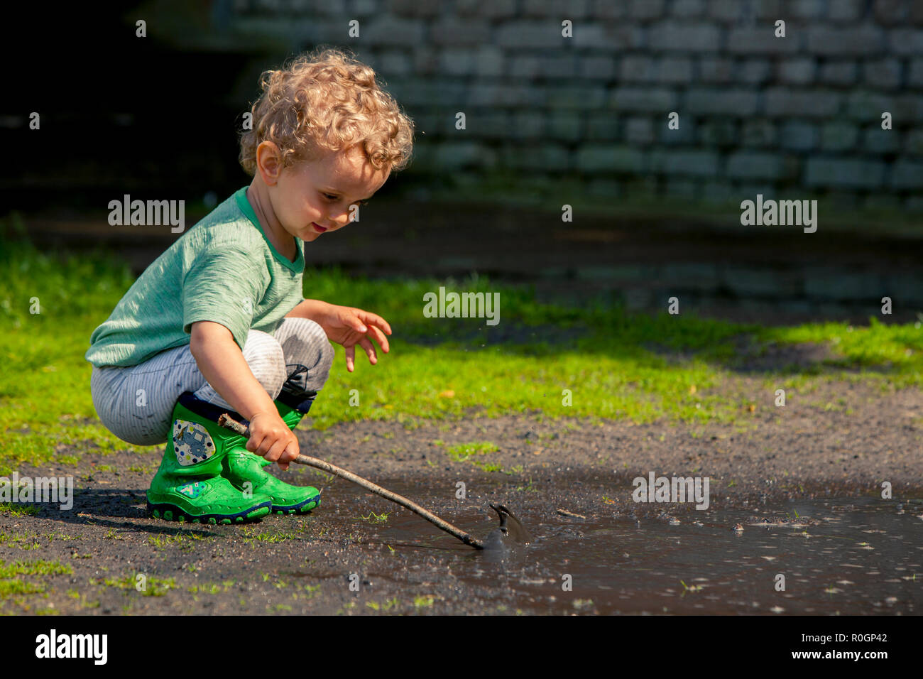 Boy playing in puddle Stock Photo - Alamy