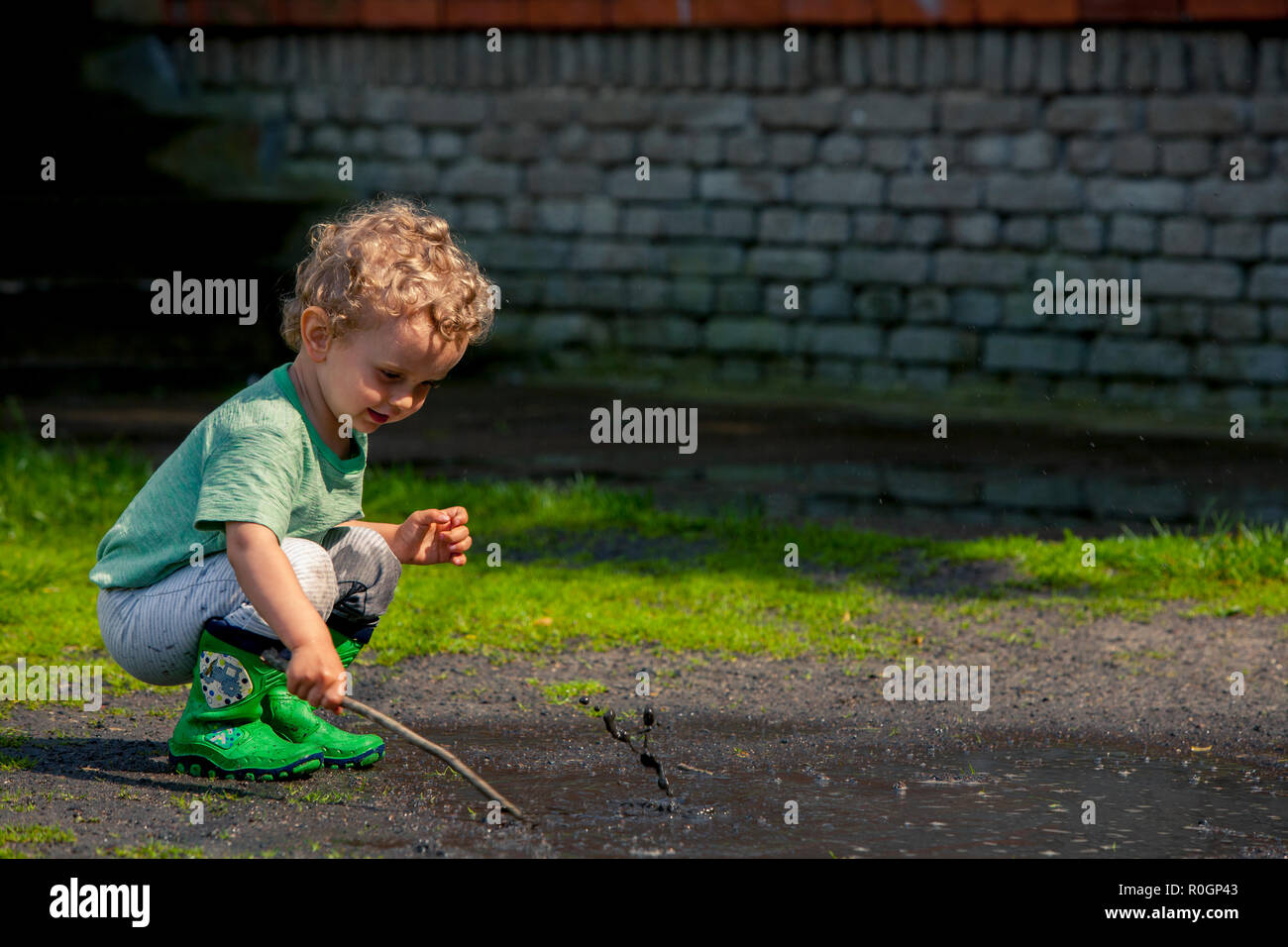 Boy playing in puddle Stock Photo - Alamy