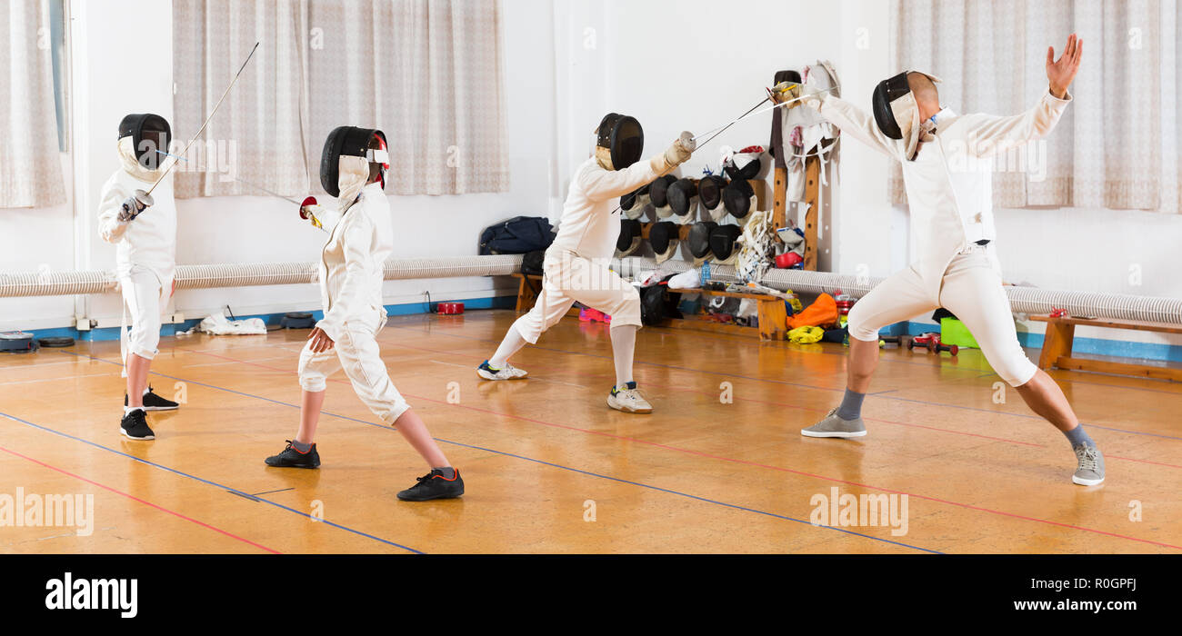 Portrait of young fencers with trainer engaged in fencing in training ...