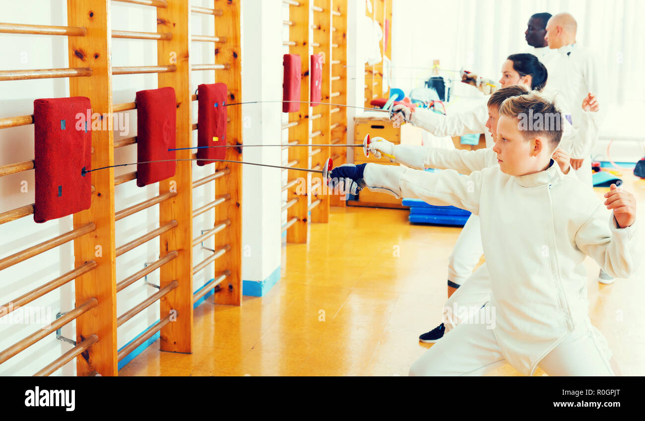 Kids with adults practicing effective techniques of fencing in training ...