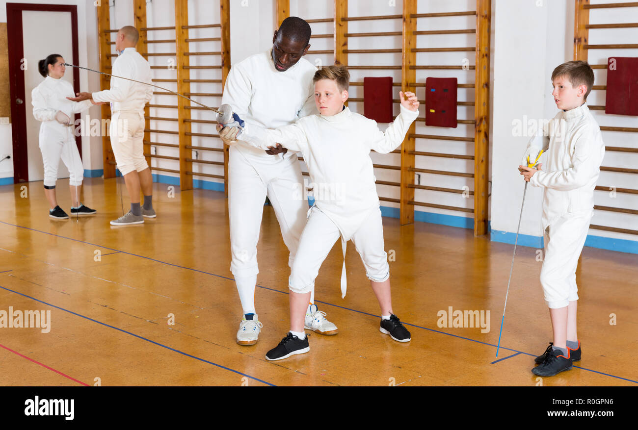 Fencing instructor explaining to young fencers effective movements and ...