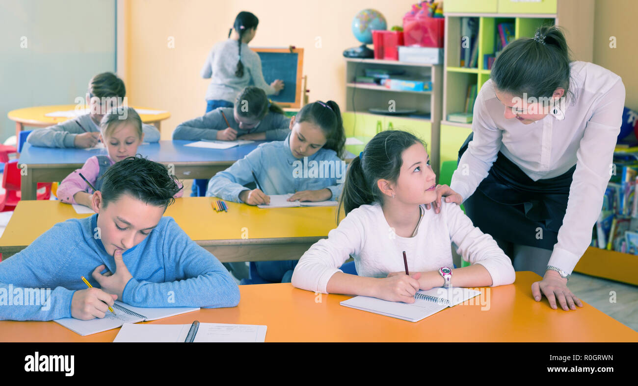 Woman teacher helping drawing to group kids 9-10 years old at class ...