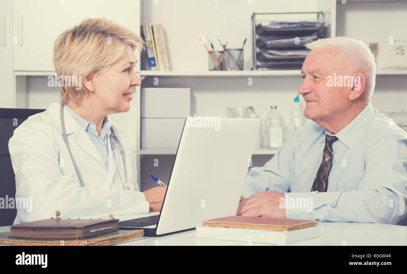 Mature male client visiting consultation with woman doctor in hospital ...