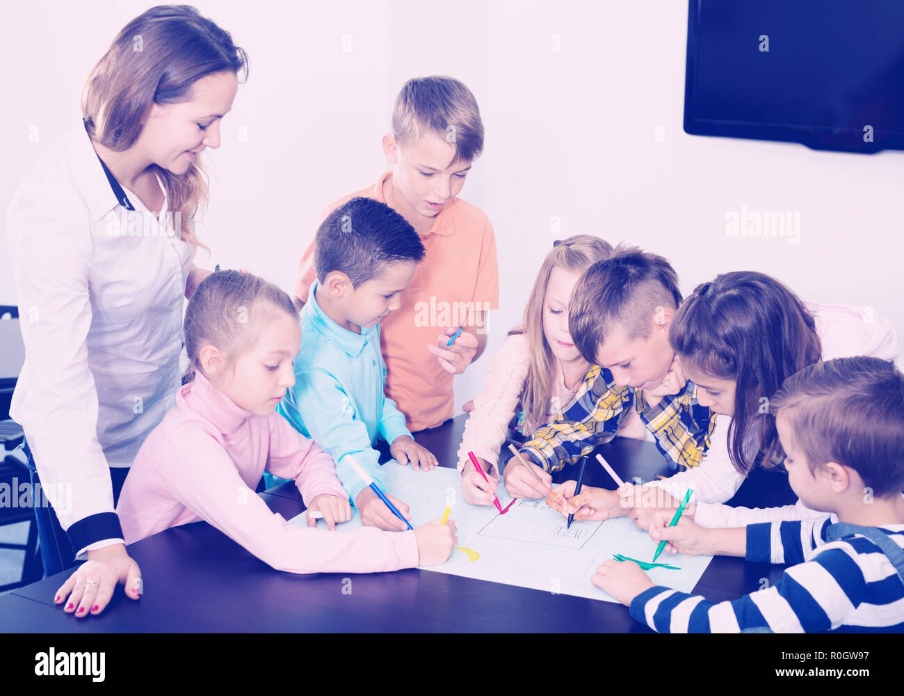 Team of elementary age children drawing on one sheet Stock Photo - Alamy