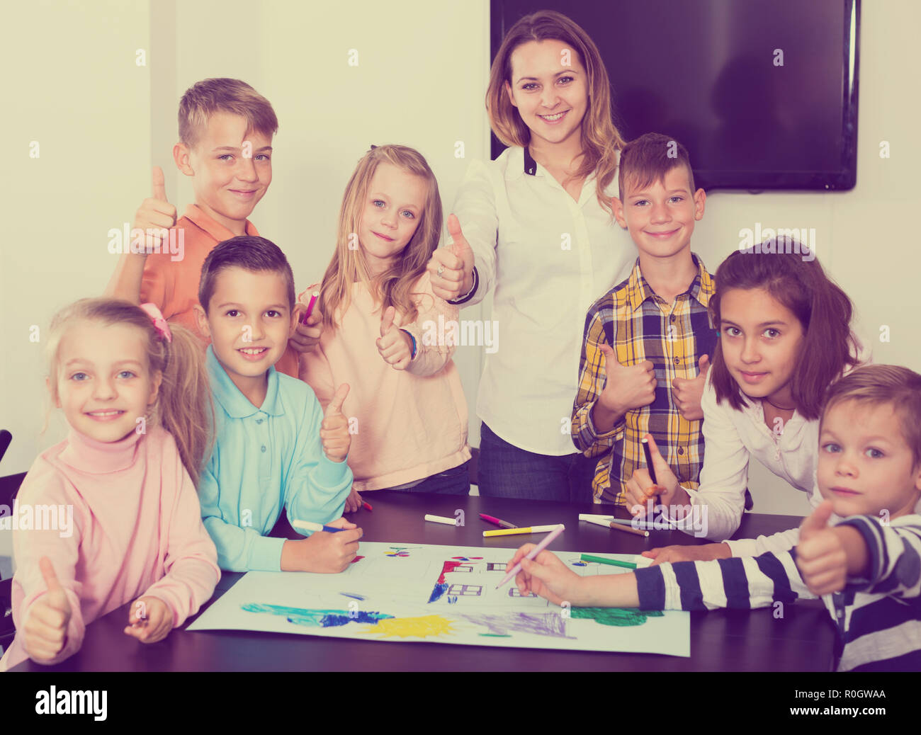 Portrait happy team of elementary age children drawing on one sheet ...