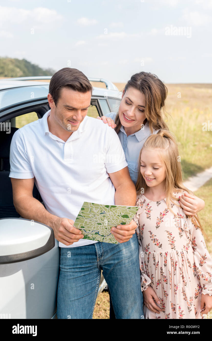 beautiful family looking at map together during car trip in field Stock ...