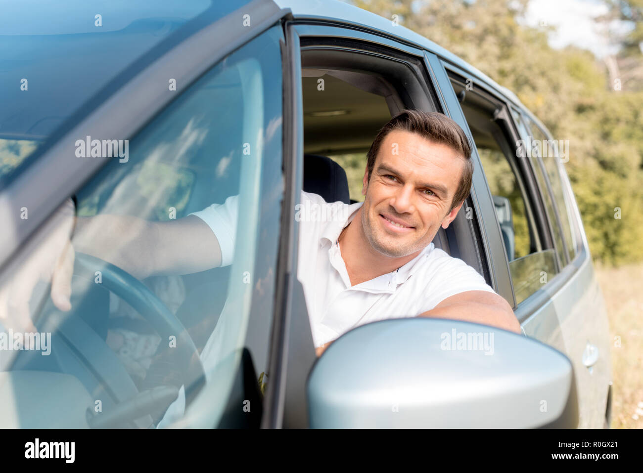 happy man looking out window while driving car in field Stock Photo - Alamy