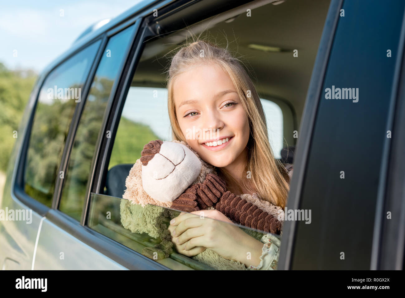 close-up portrait of smiling little child riding car on nature with ...