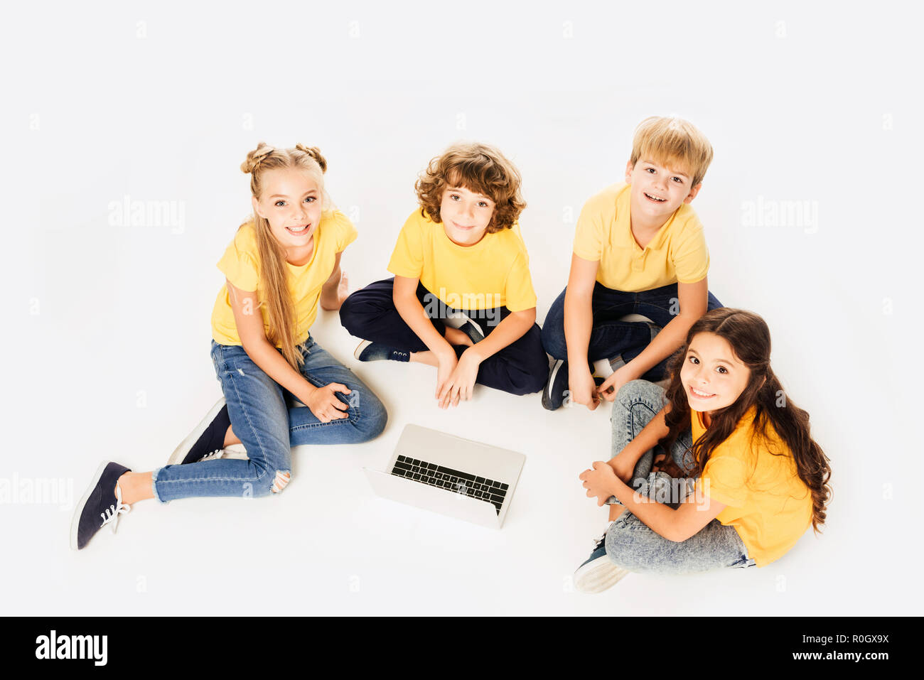 high angle view of happy kids using laptop and smiling at camera ...