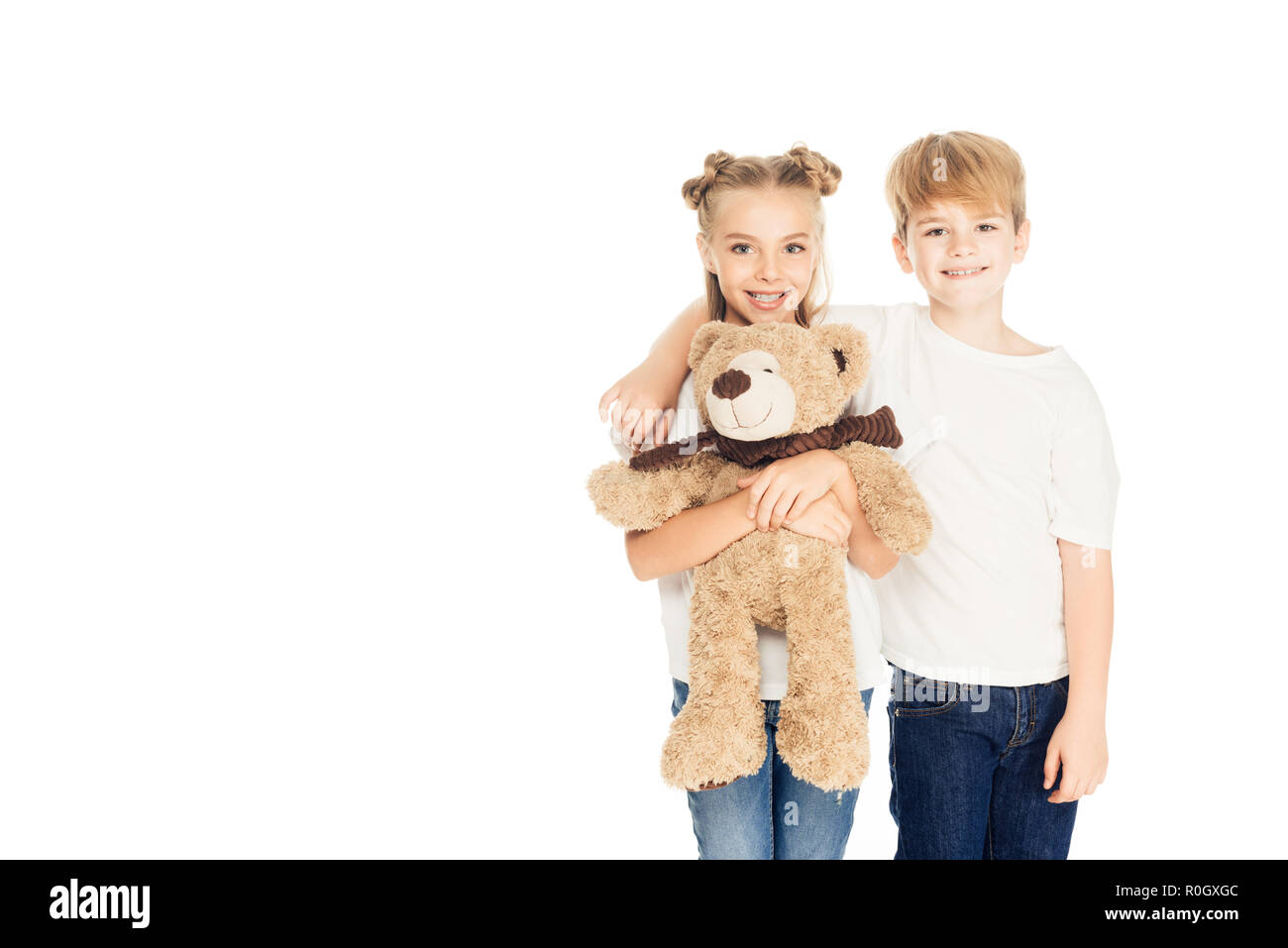 cheerful kids hugging, holding teddy bear and looking at camera ...