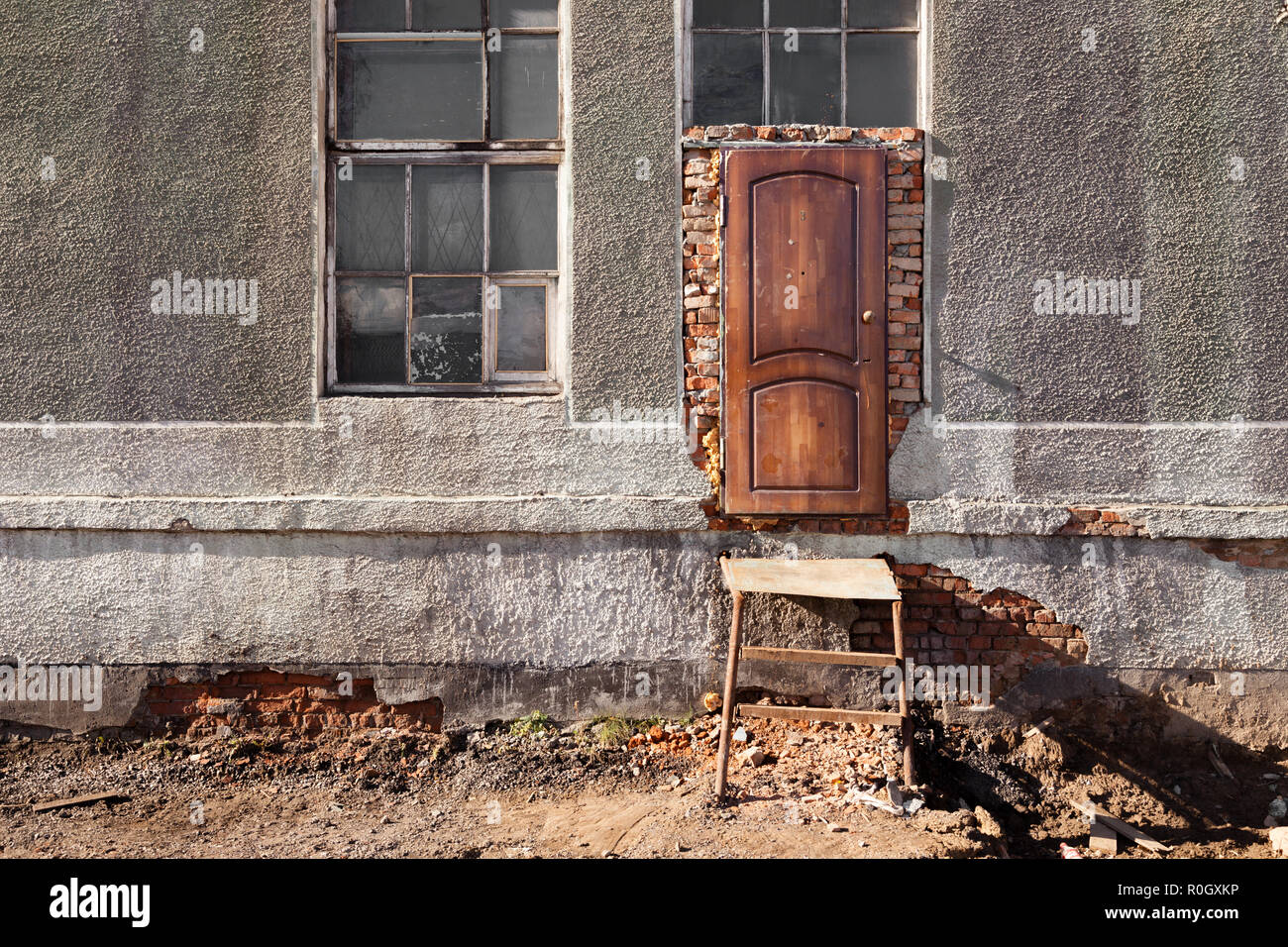 Entrance to the destroyed building, wooden door, metal staircase ...