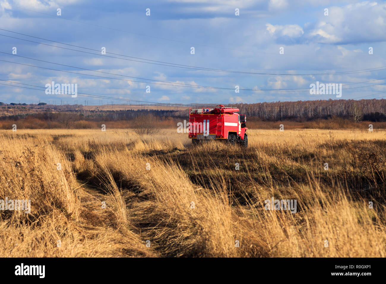 Red firetruck car Ural rides through the autumn field with yellow and ...