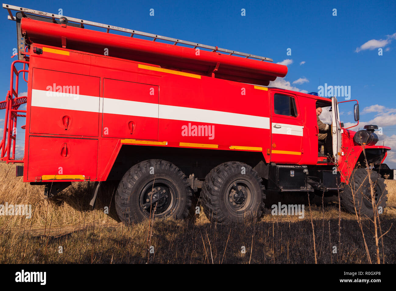 Red firetruck car Ural rides through the autumn field with yellow and ...