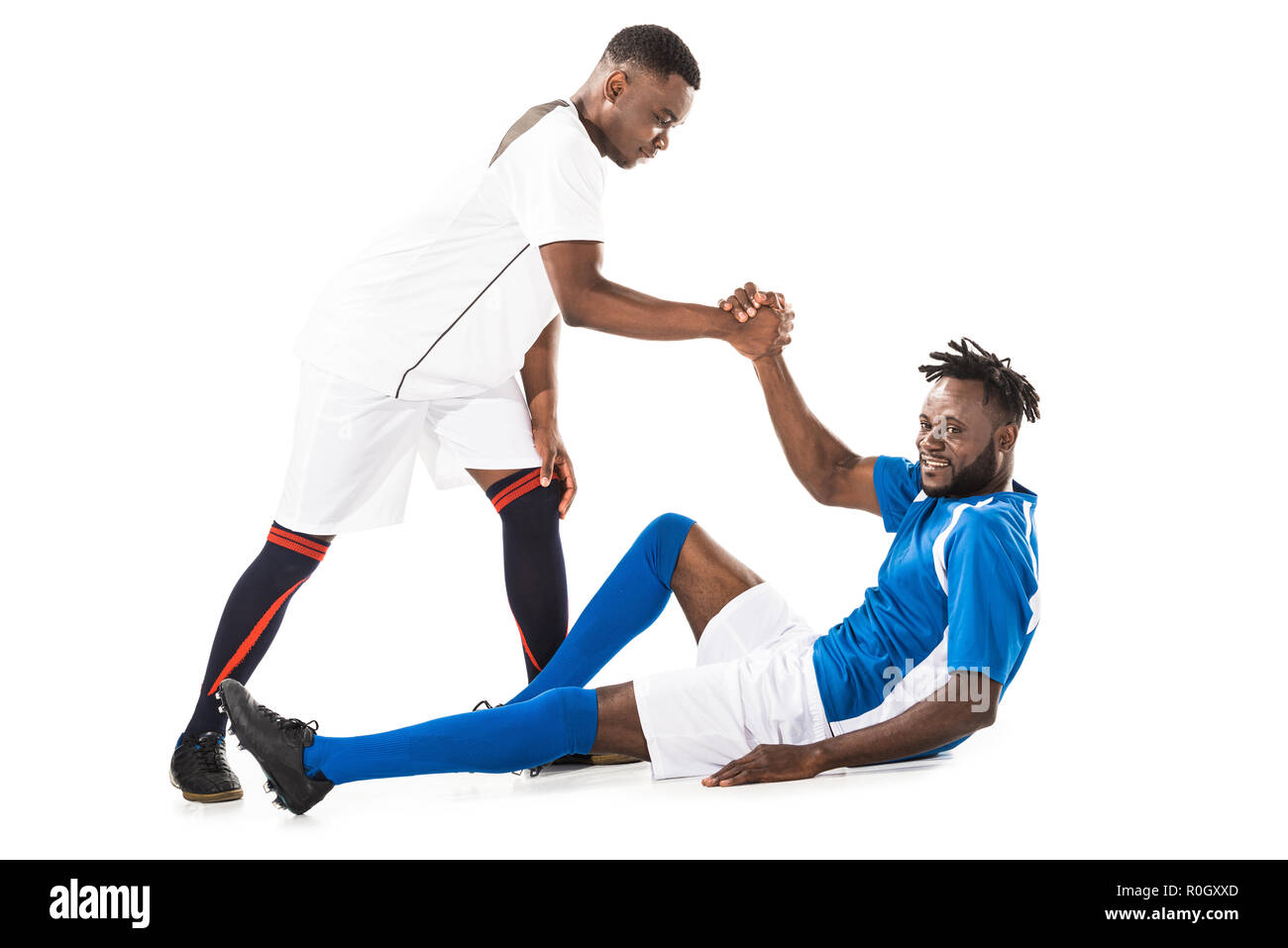 young african american sportsman helping soccer player lying isolated ...