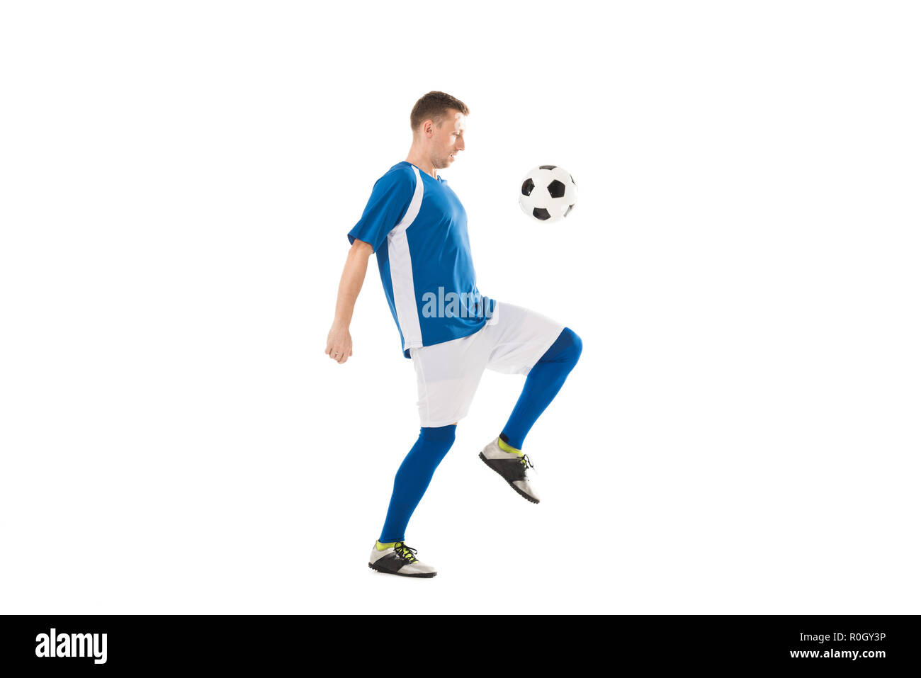 side view of young soccer player training with ball isolated on white ...