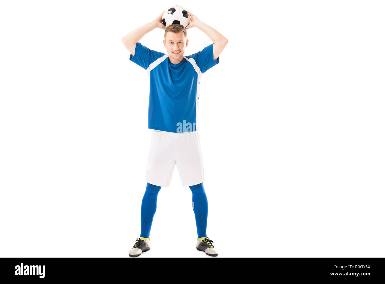 full length view of happy young soccer player holding ball above head ...