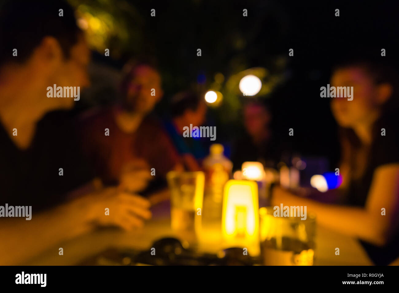 People talking at candle light, unrecognizable faces, intentional out ...