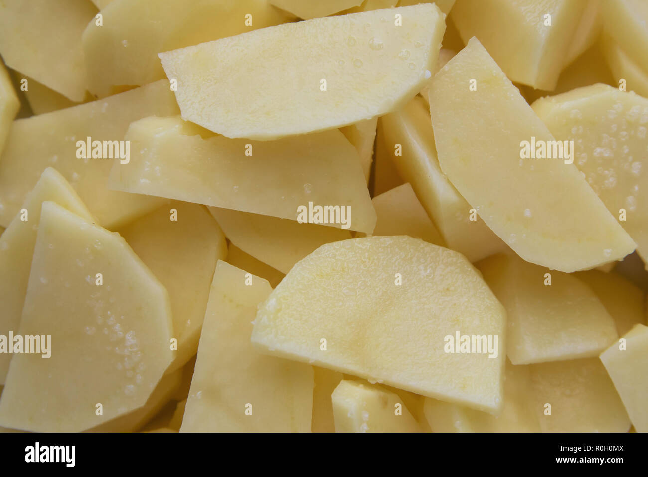 Uncooked cubical yellow potatoes on a chopping board. In the chopped ...