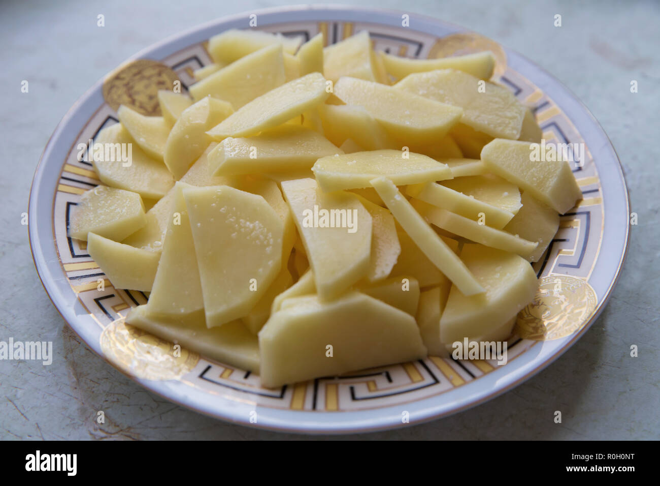 Uncooked cubical yellow potatoes on a chopping board. In the chopped ...