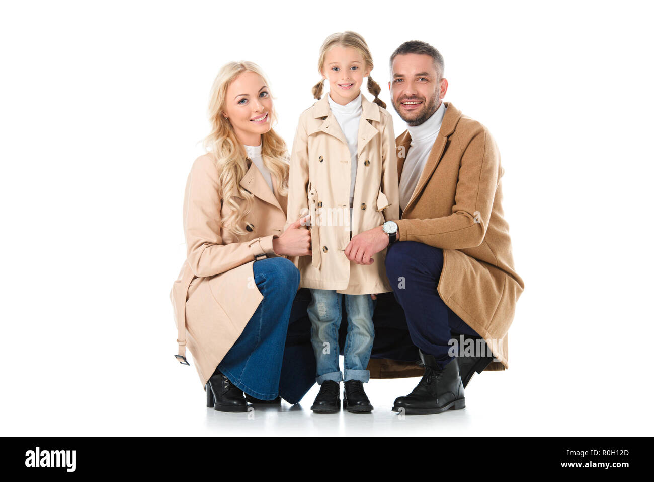 beautiful parents with adorable daughter in beige coats, isolated on ...