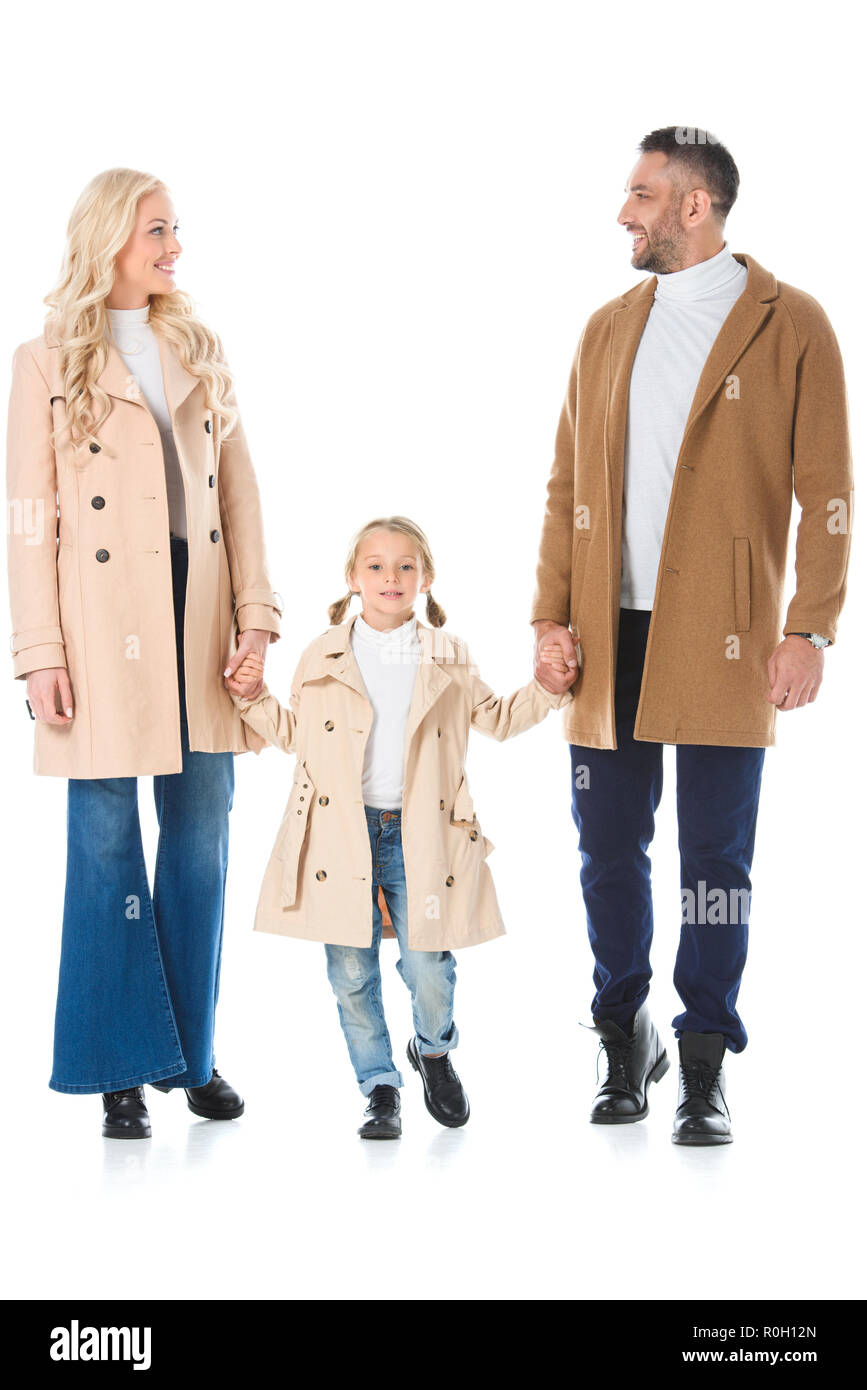 beautiful parents holding hands with daughter and posing in beige ...