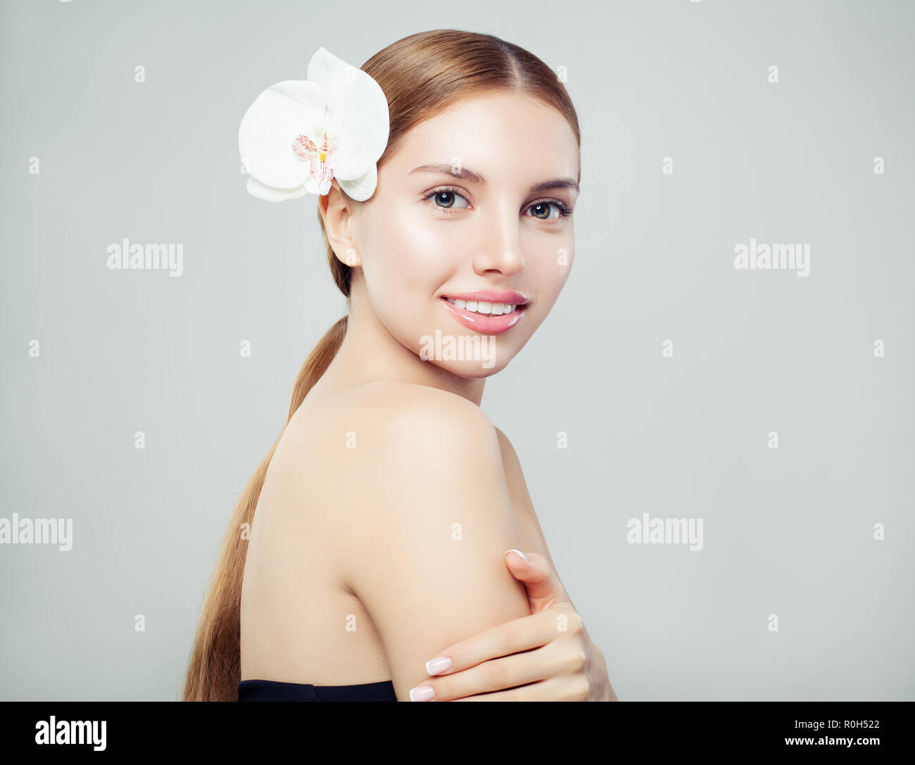 Healthy woman spa model with long hair, clear skin and orchid on white ...