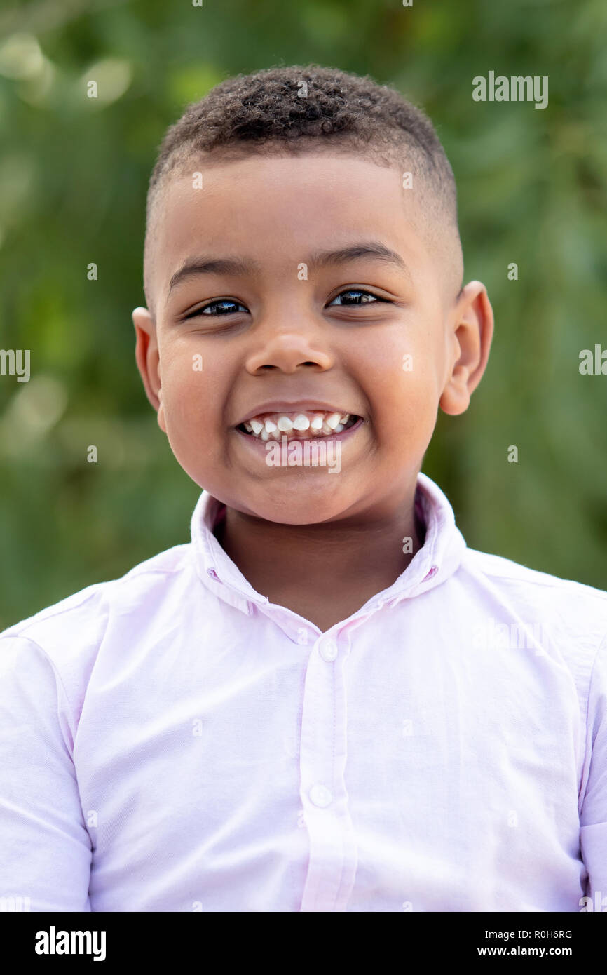 Adorable latin child in the garden with a beautiful green of background ...