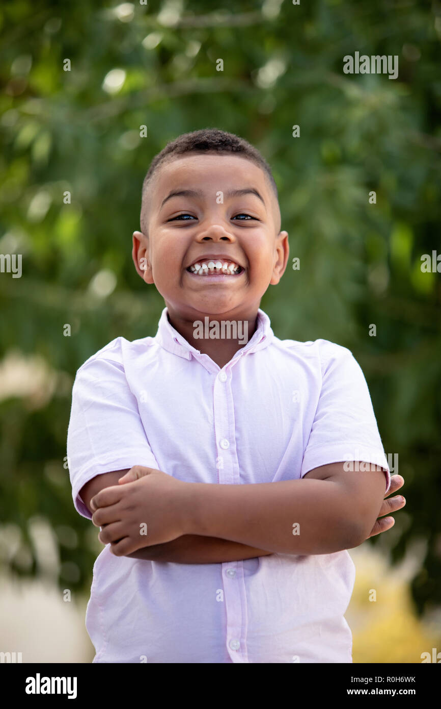 Adorable latin child in the garden with a beautiful green of background ...