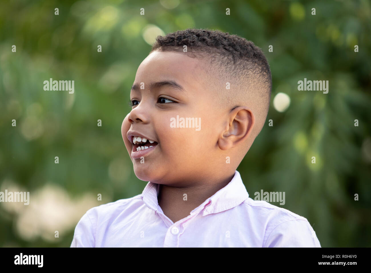 Adorable latin child in the garden with a beautiful green of background ...