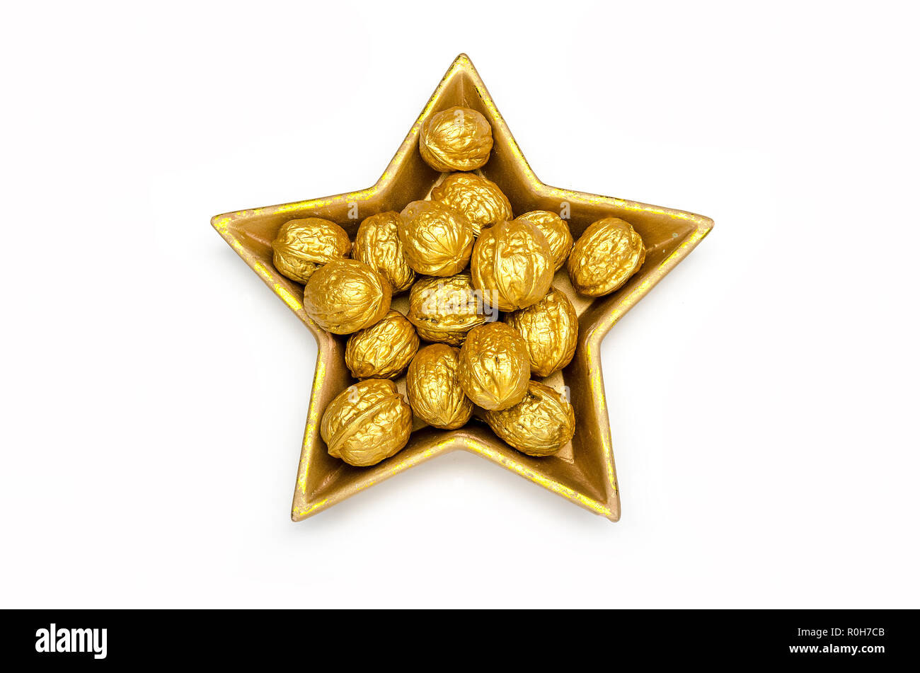 some golden walnuts in a golden star shaped bowl on a white background ...