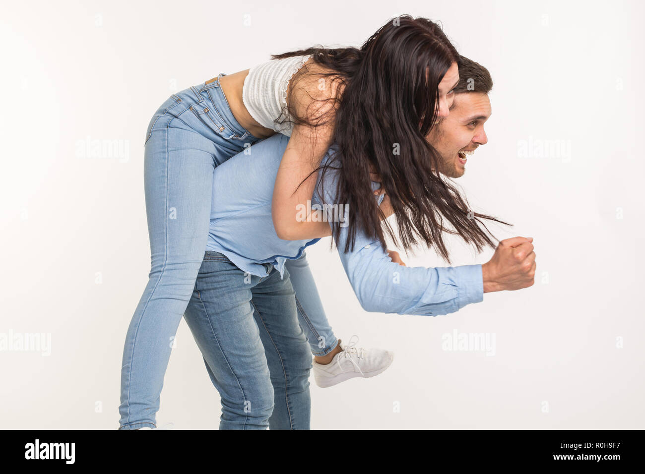 Young male carrying his girlfriend piggyback. They are fooling around ...
