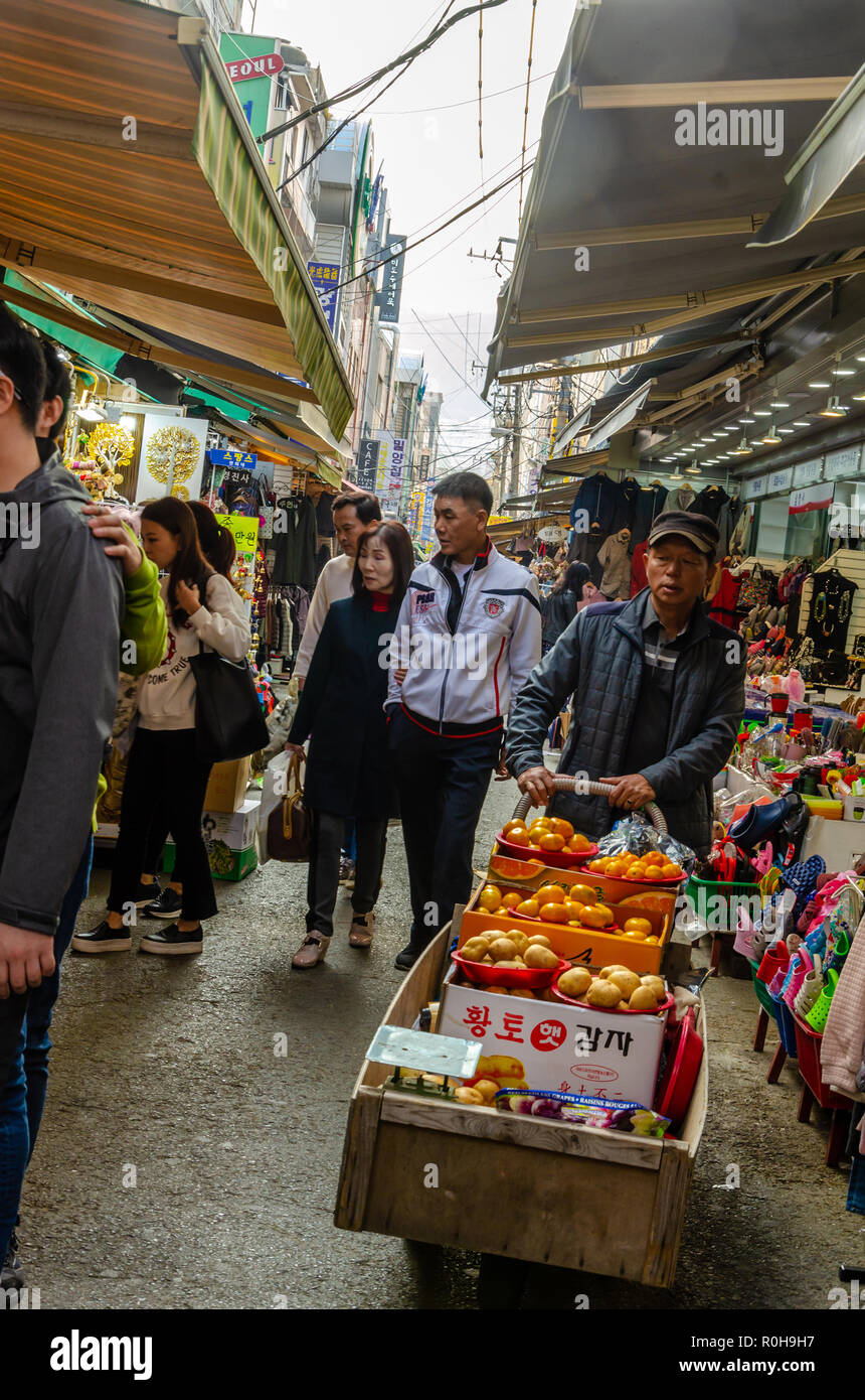 Busy street market scene in Busan, South Korea. A man pushes a push ...
