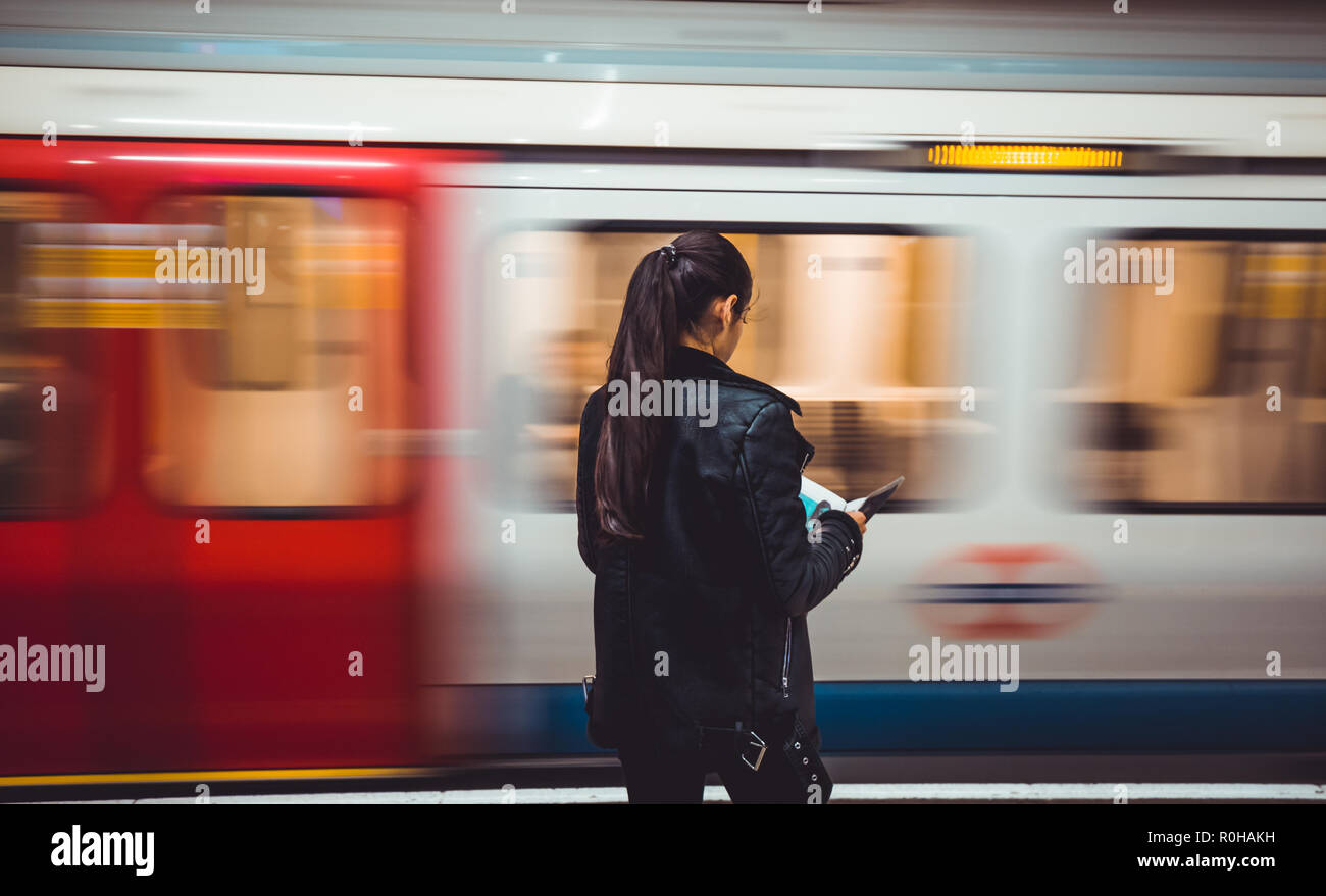 LONDON - OCTOBER 31, 2018: Young woman reading magazine as speeding ...