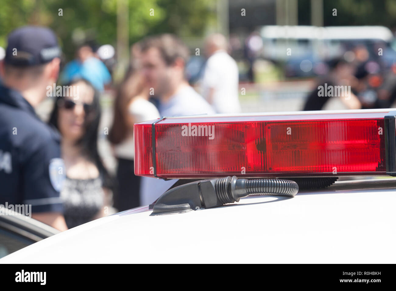Police car flashing lights in focus, blurred people in the background ...