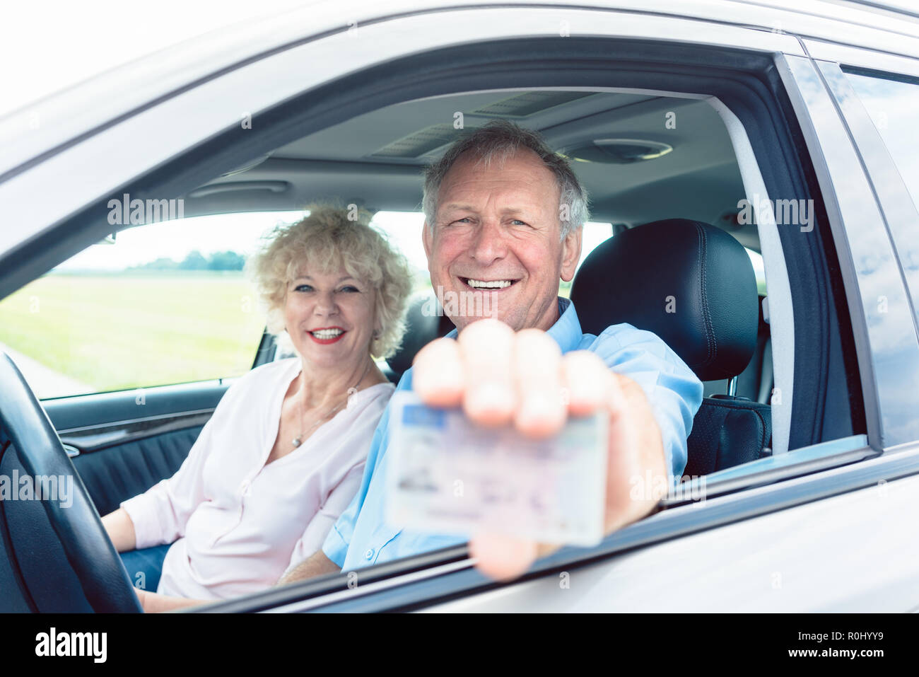 Portrait of a happy senior man showing his driving license while Stock ...