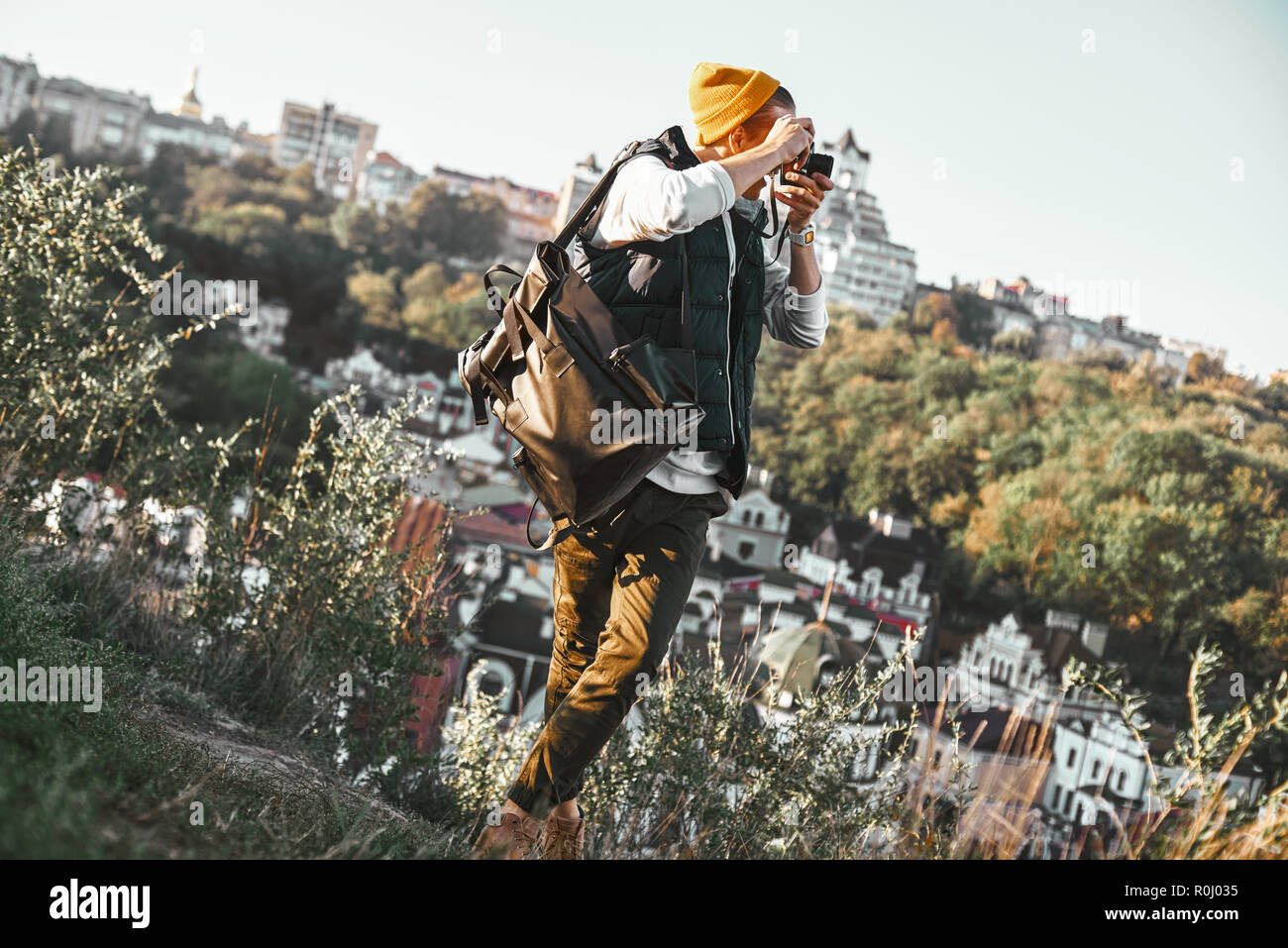 Back view of a young man tourist taking photo of of retro buildings ...