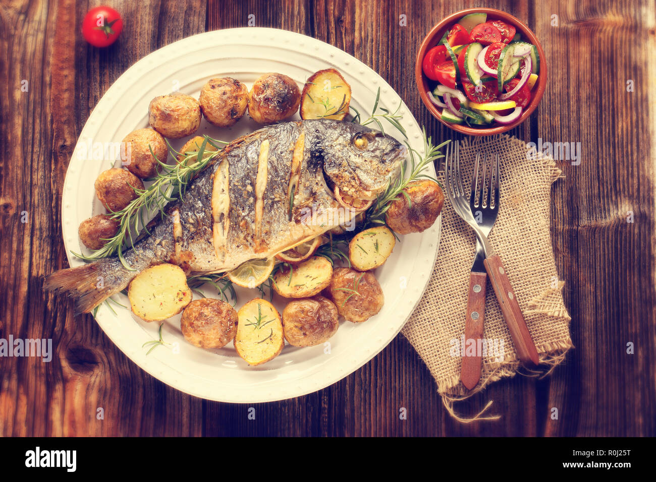 Grilled dorada fish with roasted potatoes and vegetables on the plate ...