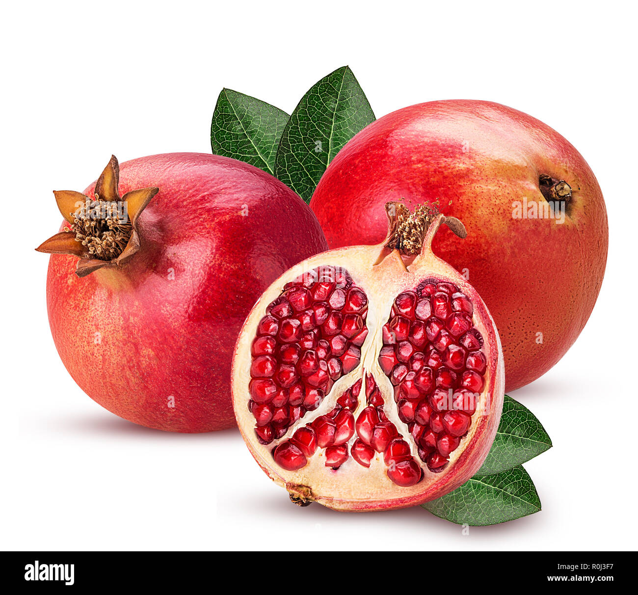 Two pomegranate and one cut in half with leaf isolated on white ...
